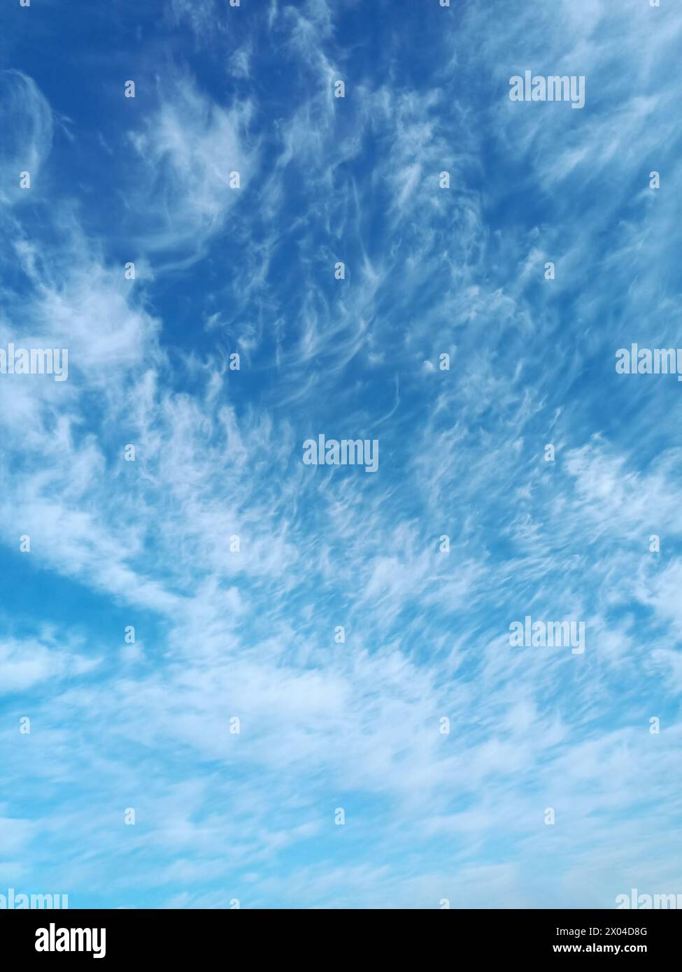 Cluster of high-altitude cirrus cumulus clouds against the background of the blue sky in April ...