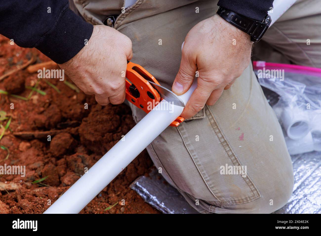 Plumber cuts plastic PVC pipe with special pair of scissors Stock Photo ...