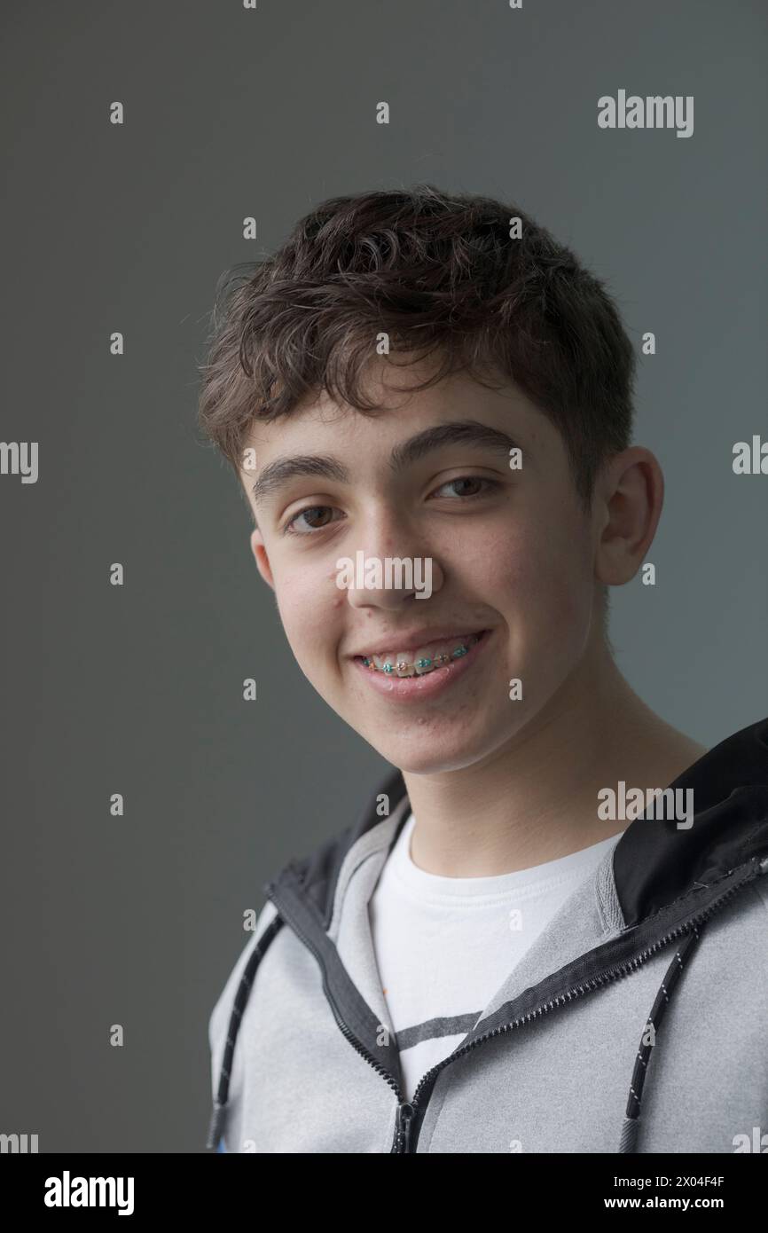 Vertical portrait with gray background of a teenage boy with braces on ...