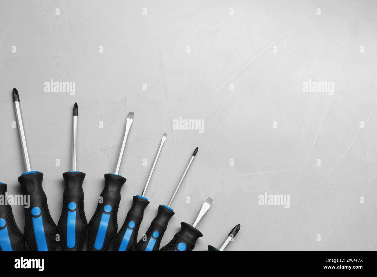 Set of screwdrivers on light grey background, flat lay. Space for text ...