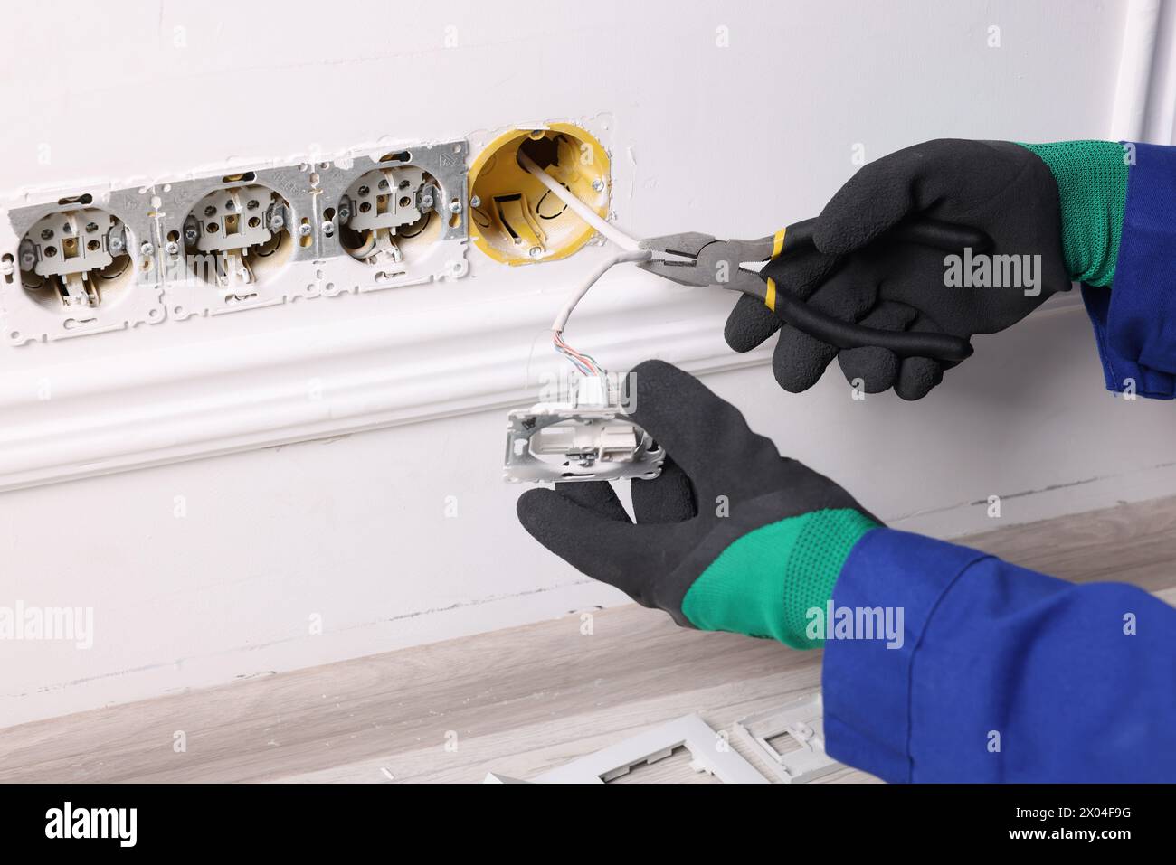 Professional repairman fixing power sockets with pliers indoors ...