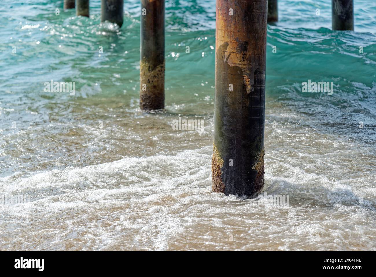 View on sea water splashing at wooden pier pillars Stock Photo - Alamy