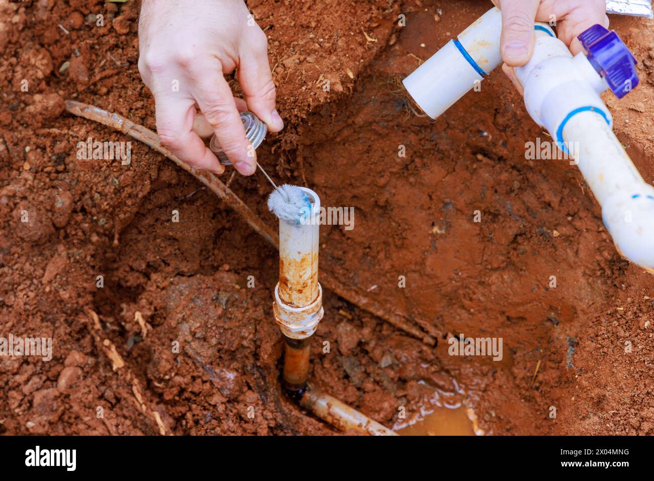 Plumber technician uses clear primer before gluing PVC pipe as part of ...