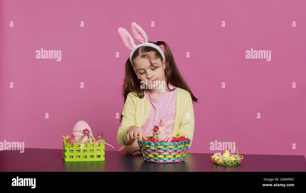 Sleepy little girl yawning while she arranges easter eggs for festive ...