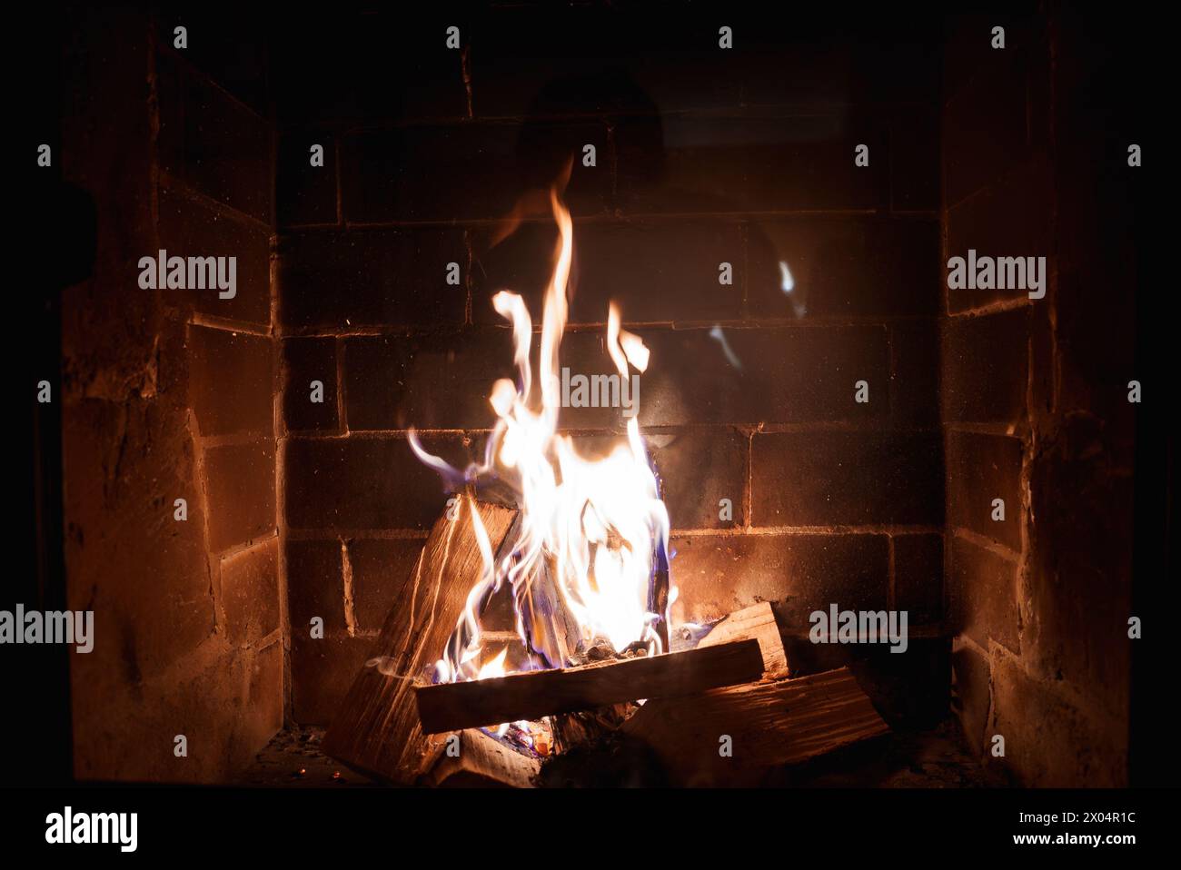 Brick fireplace with cozy wood fire burning, warm glow Stock Photo - Alamy