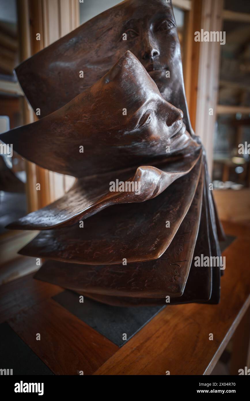 Bronze sculpture with folded planes, human face emerging indoors Stock ...