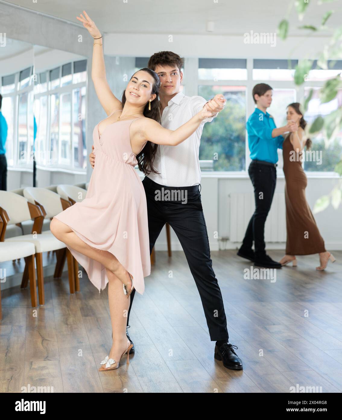 Couple in evening dresses enjoys pair dance tango, interacting with ...