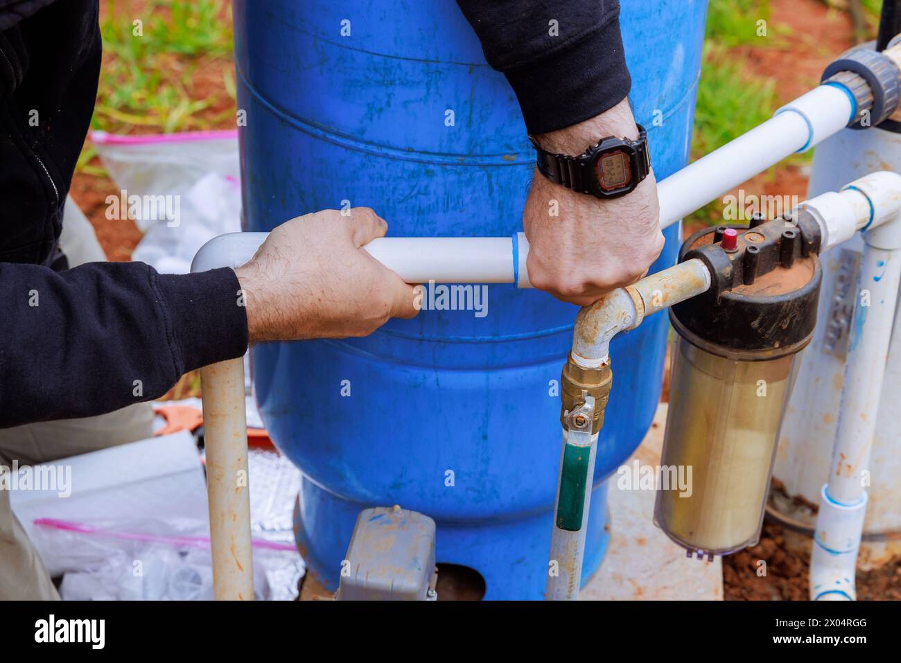 Plumber connects water to well pump for new house Stock Photo - Alamy