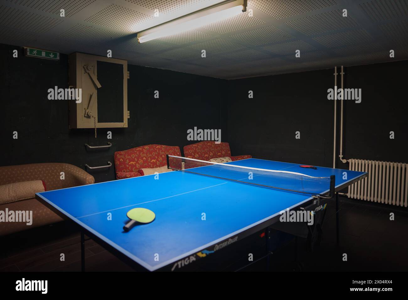 Recreational Setup with Table Tennis, Chairs, and Exit Sign in Dark ...