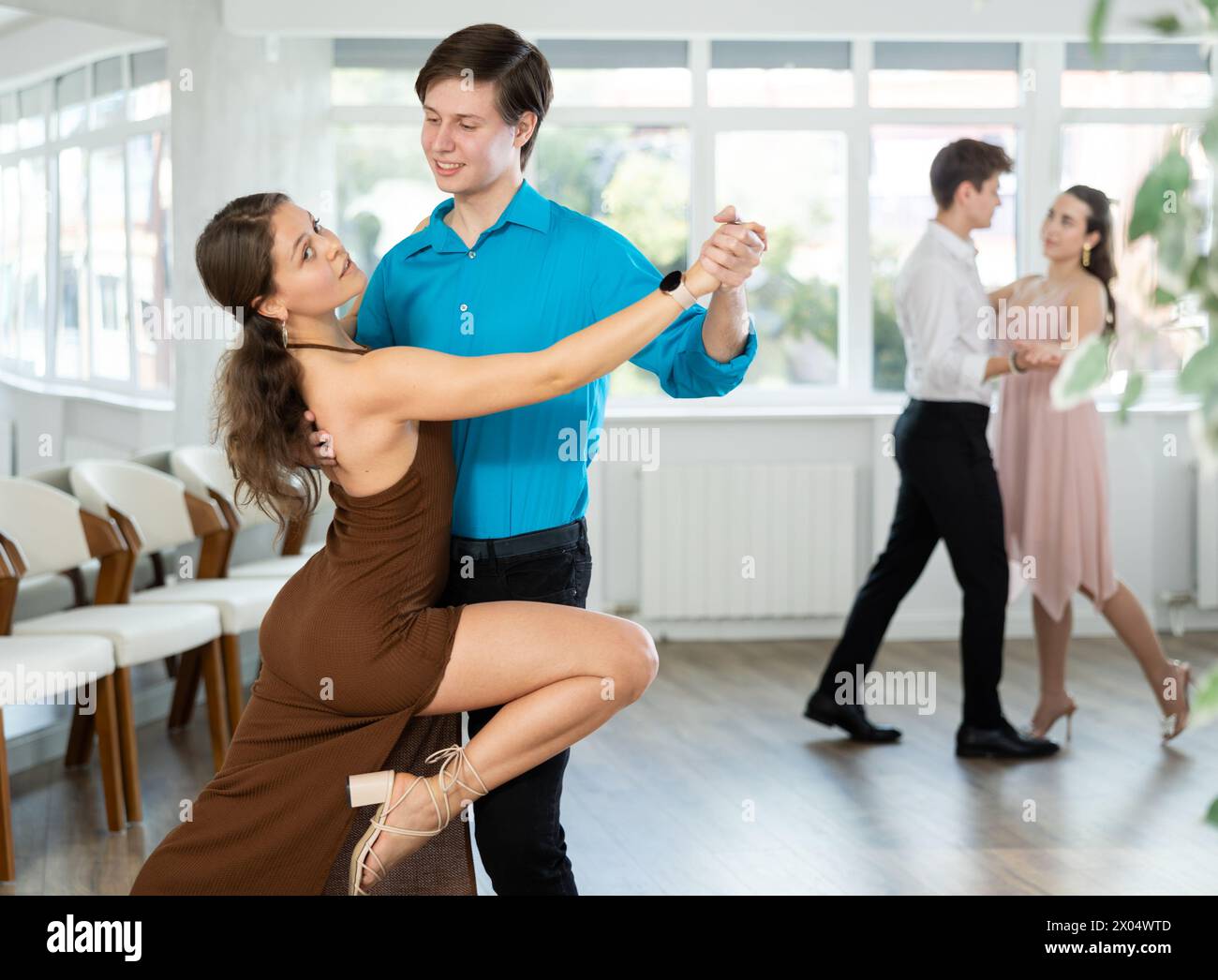 Guy rehearsing elegant tango with young female partner Stock Photo - Alamy