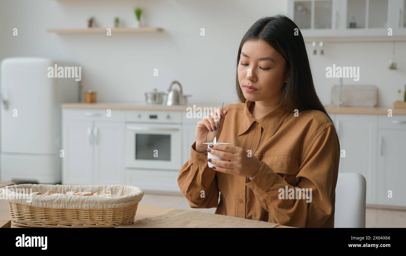 Chinese girl eat healthy natural yogurt in domestic kitchen Asian ...