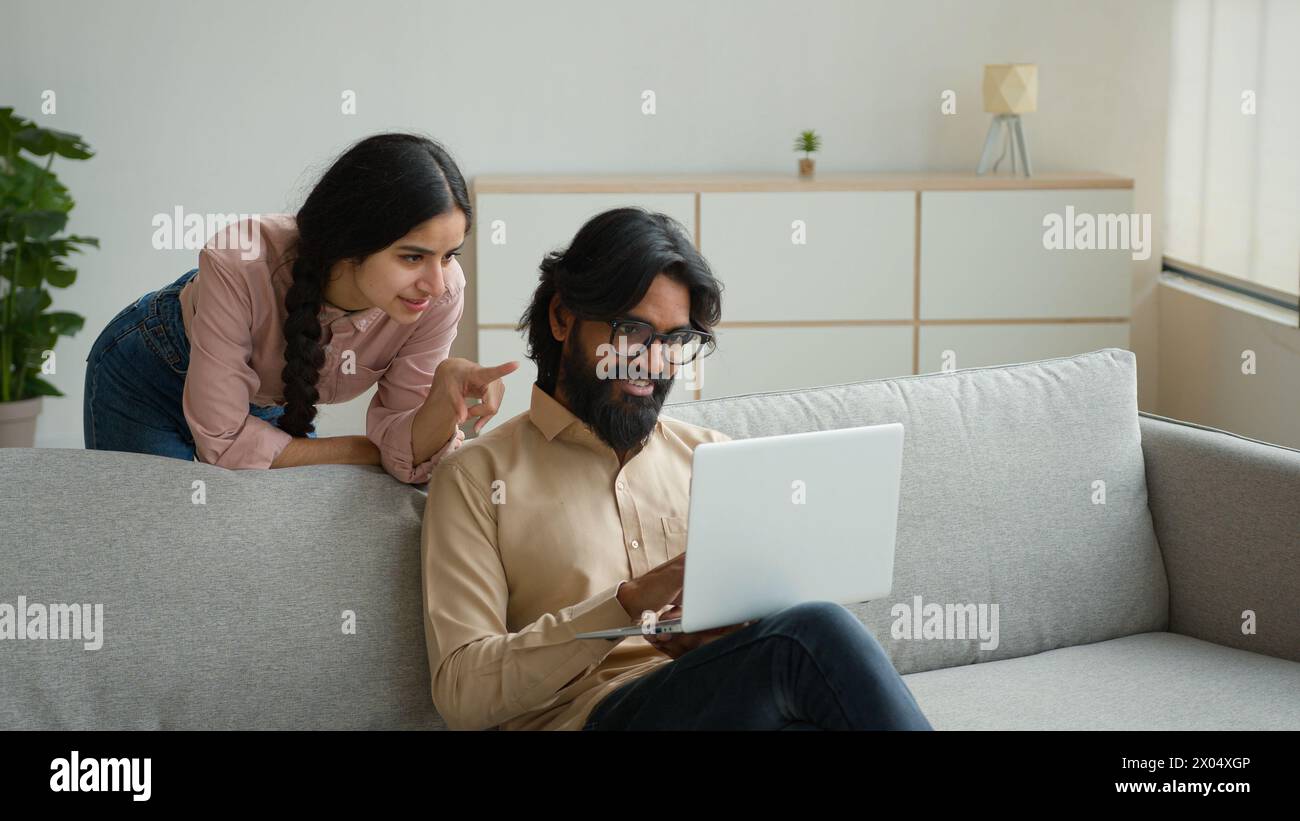 Arabian Indian couple on couch sofa use computer laptop shopping online ...