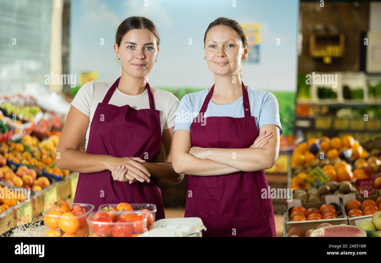 Happy two female sellers wearing apron and standing next to organic ...