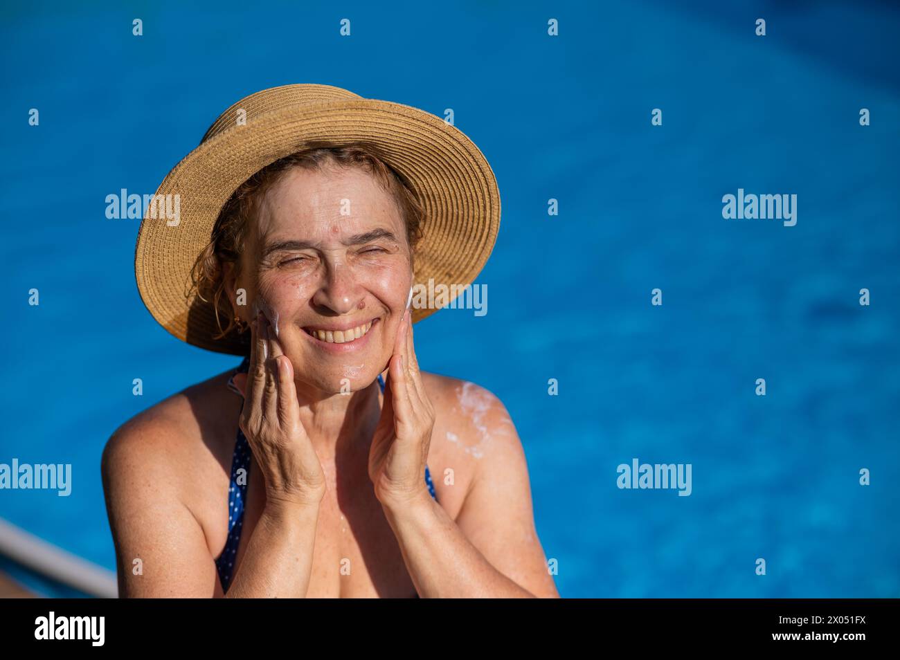 Portrait Of An Older Woman Applying Sunscreen To Her Face While On
