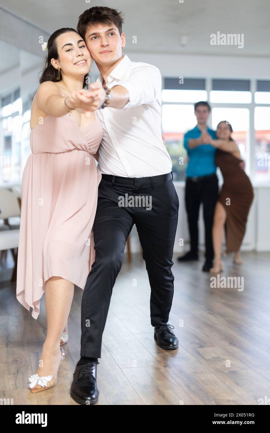 Couple in evening dresses enjoys pair dance tango, interacting with ...