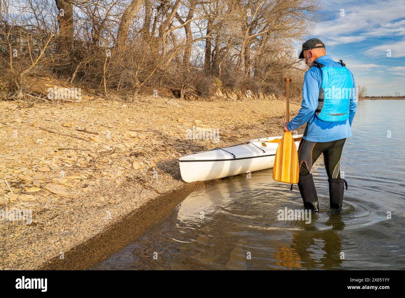 senior male paddler with expedition decked canoe on a lake shore in ...