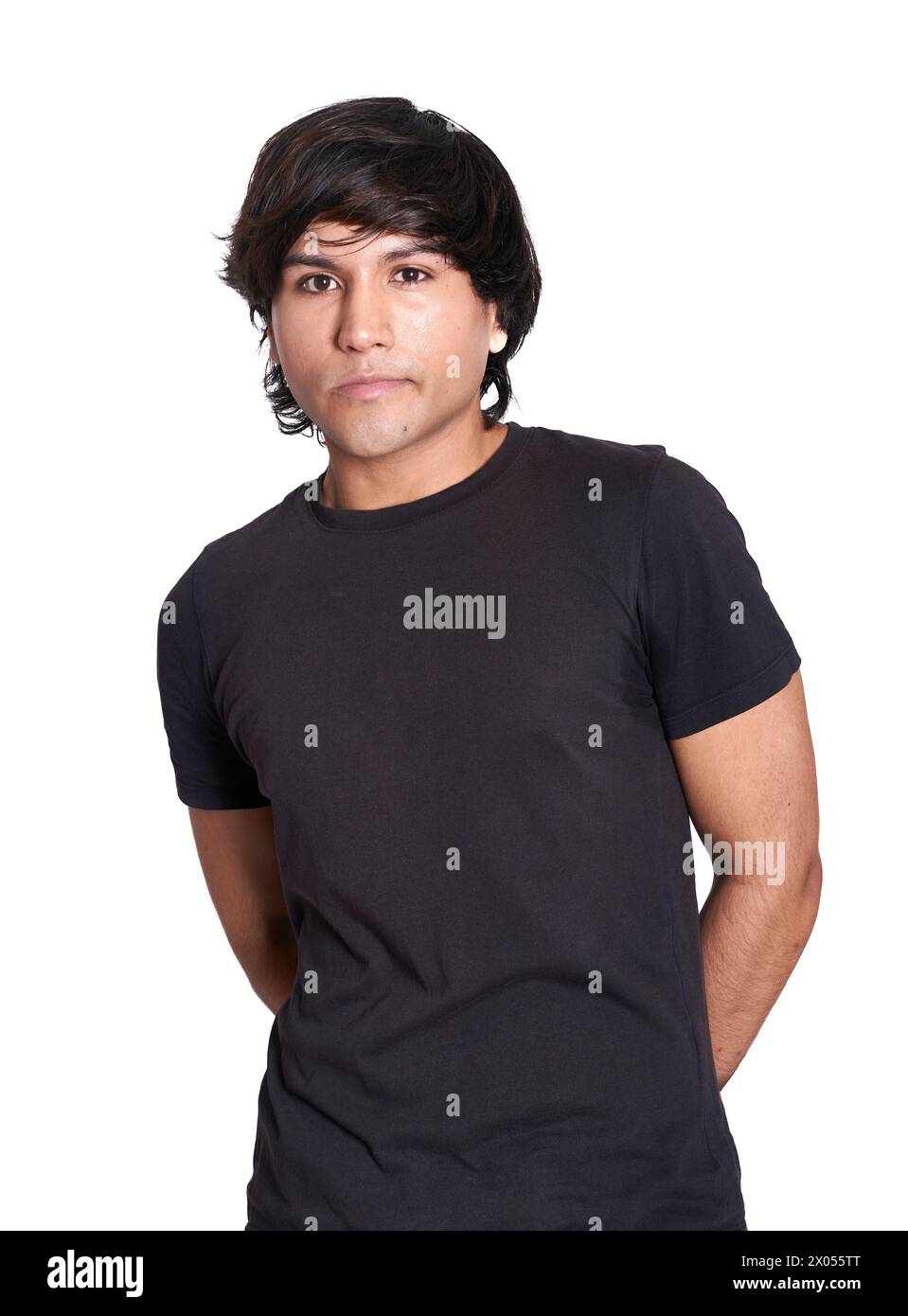 Medium shot of a young Latino man facing the camera, his hands are behind him. He looks ...