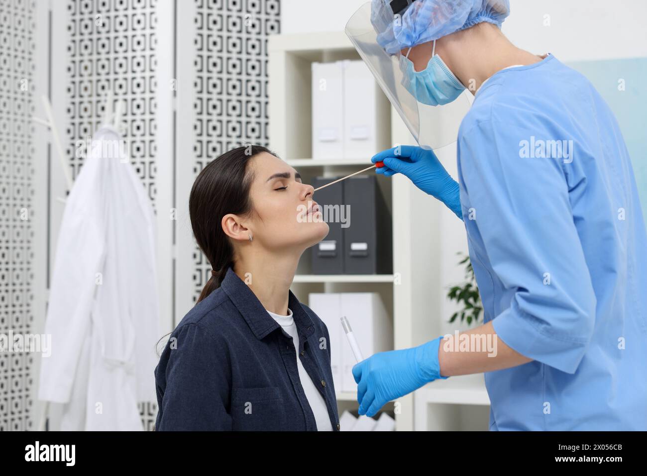 Laboratory testing. Doctor in uniform taking sample from patient's nose ...