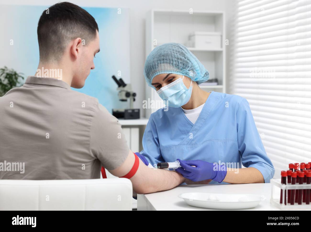 Laboratory testing. Doctor taking blood sample from patient at white ...
