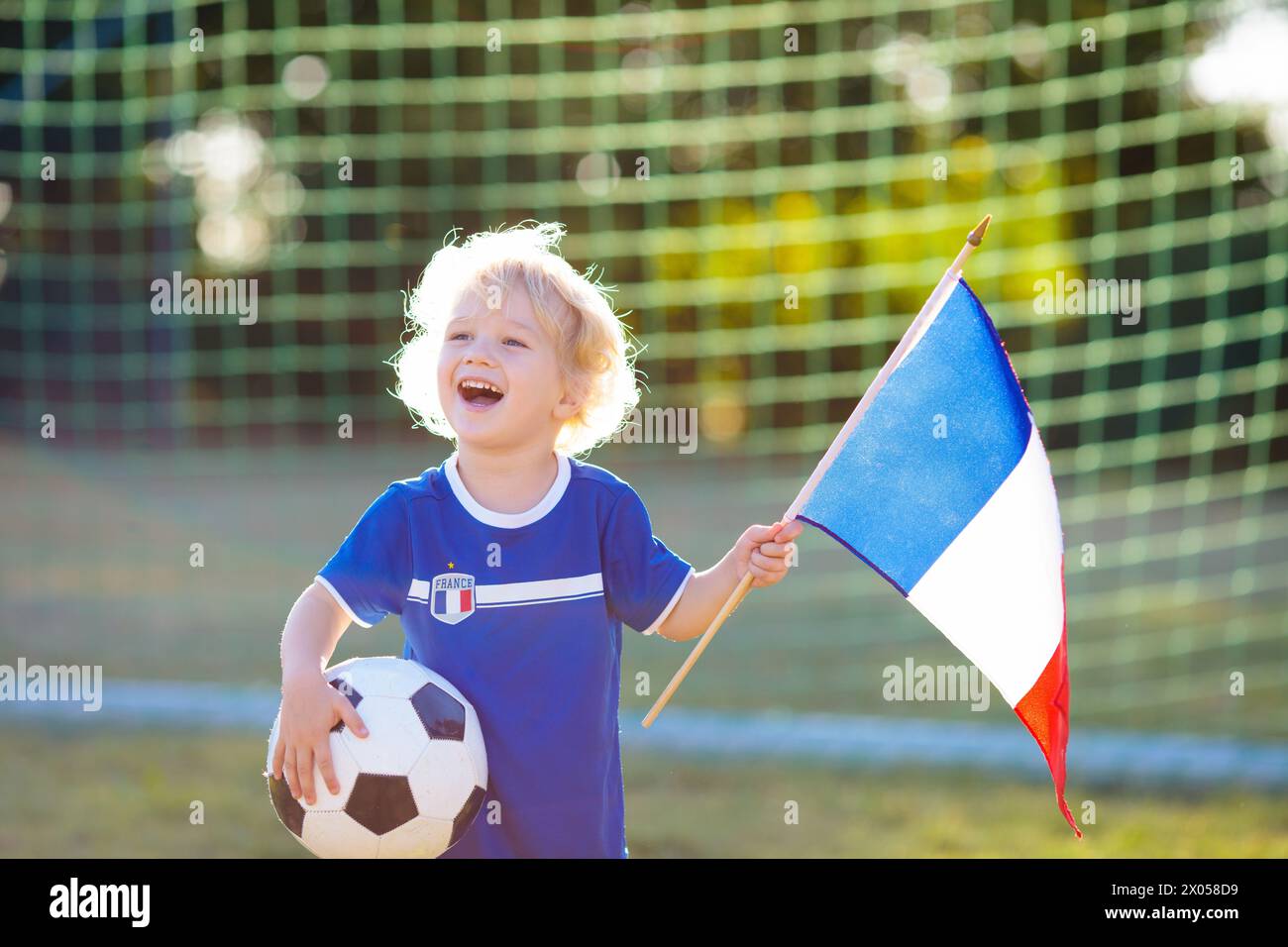 Kids play football on outdoor field. France team fans with national ...