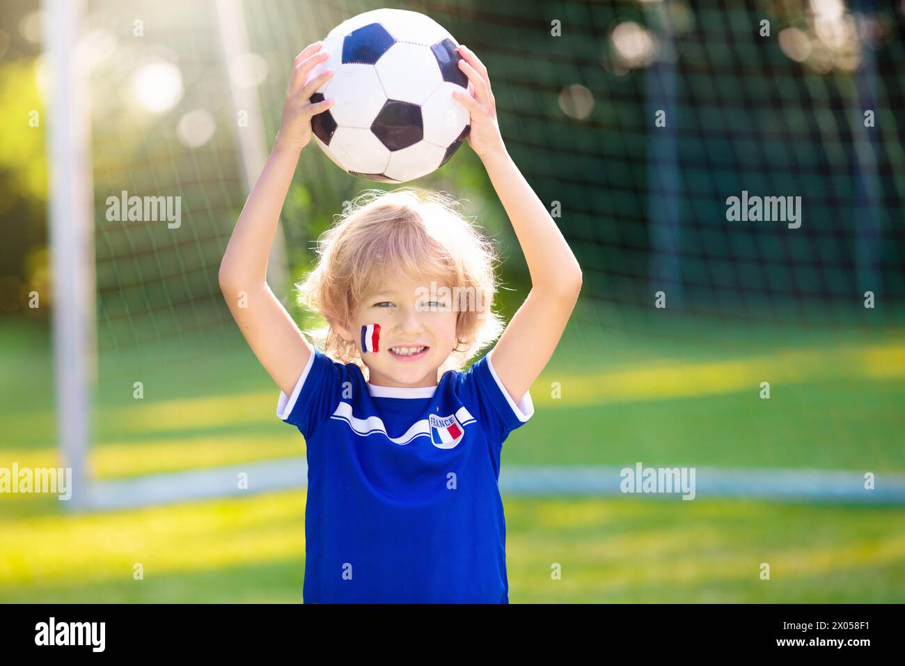 Kids play football on outdoor field. France team fans with national ...