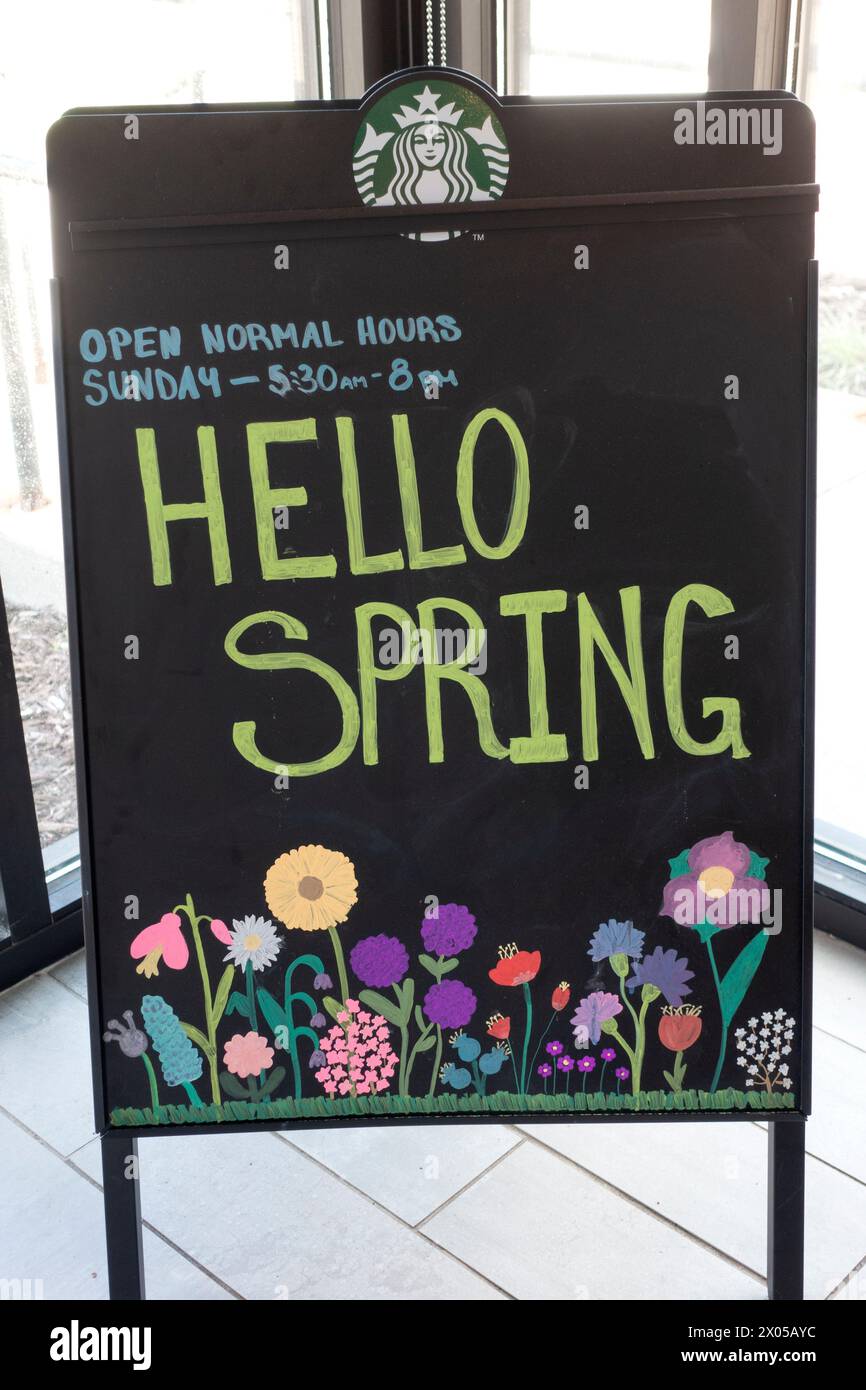 Sign on a-frame "Hello Spring" at Starbucks Coffee Shop with the hours ...