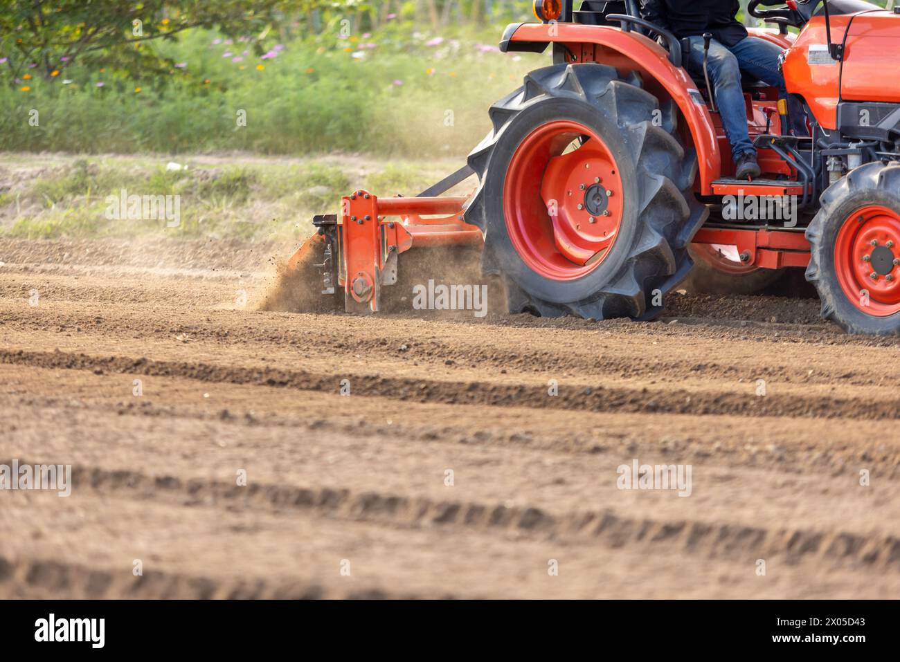 Tractor cultivating land with a rotary tiller in farm Stock Photo - Alamy