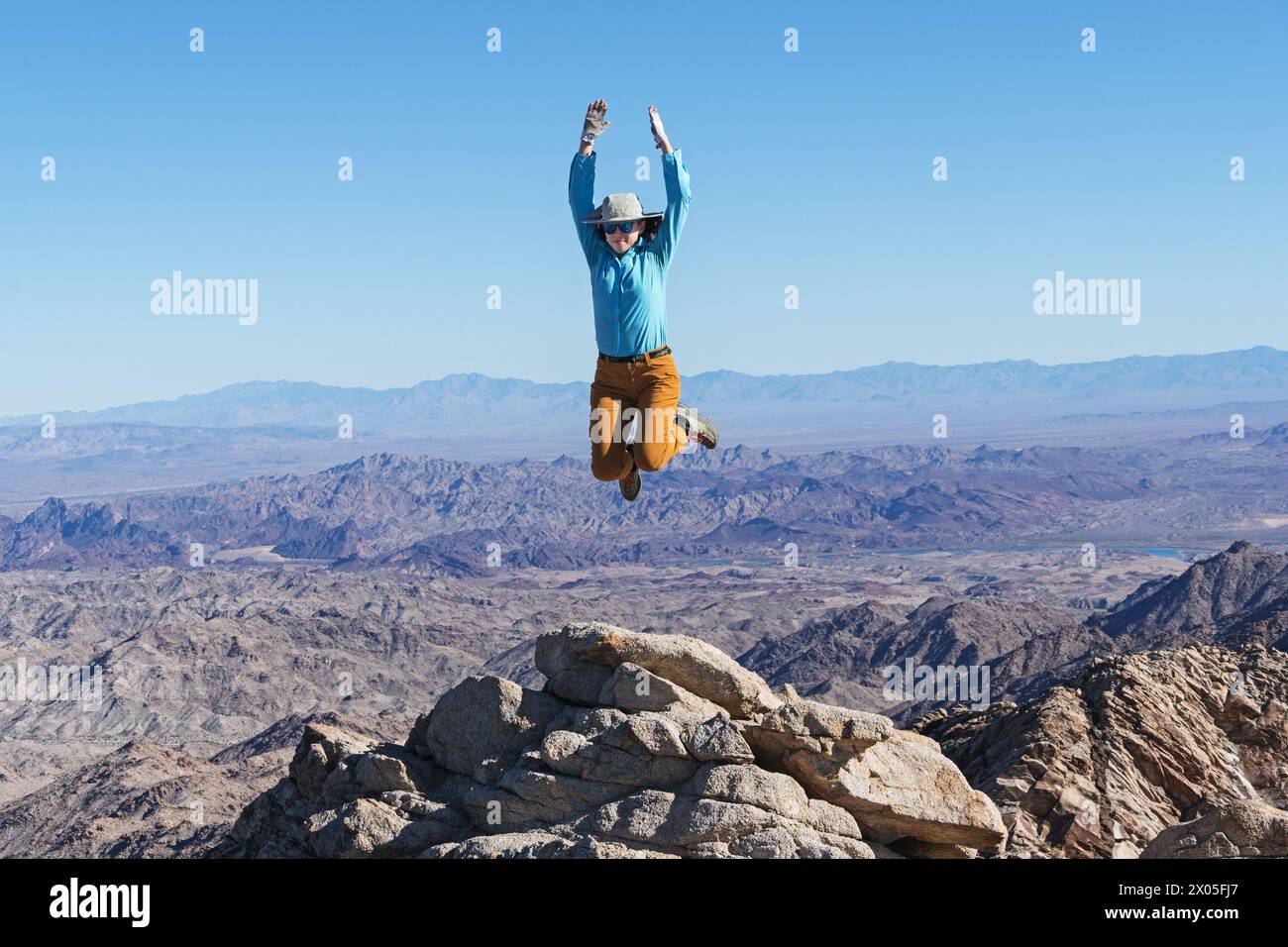 woman jumps into the air to celebrate climbing to the summit of ...