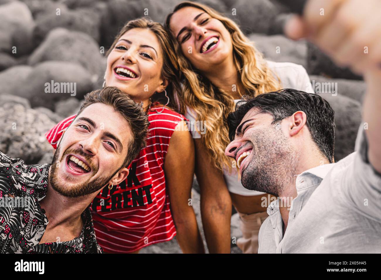 Joyful group of young adults take a playful selfie together against ...