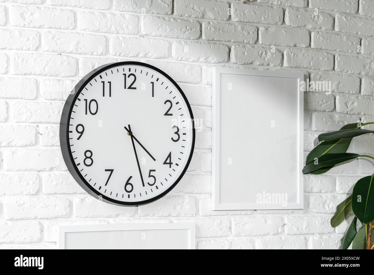 Minimalist White Wall Decor Featuring a Clock and Blank Photo Frames ...