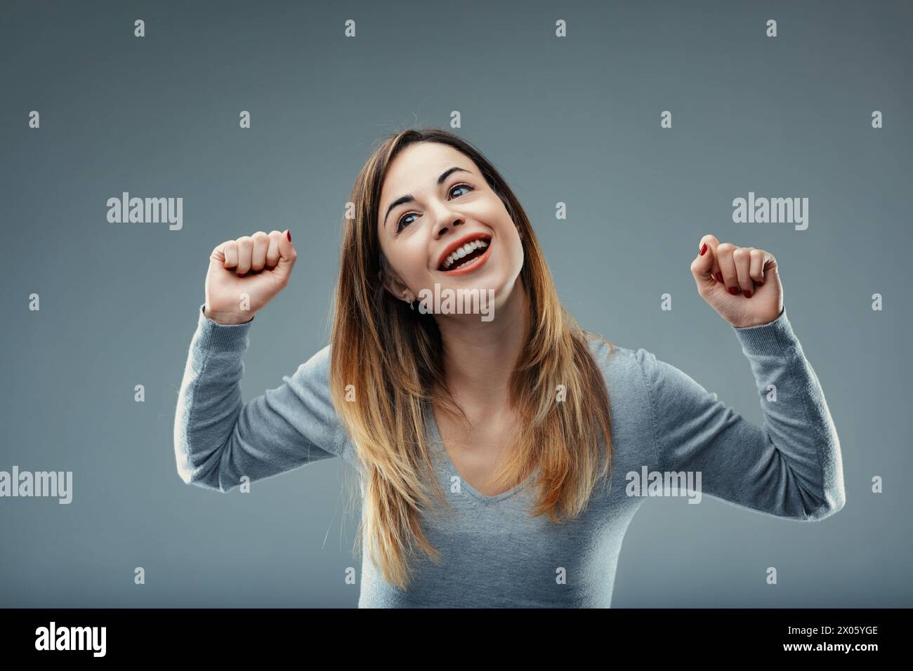 Radiant lady celebrates success with uplifted fists, her smile ...