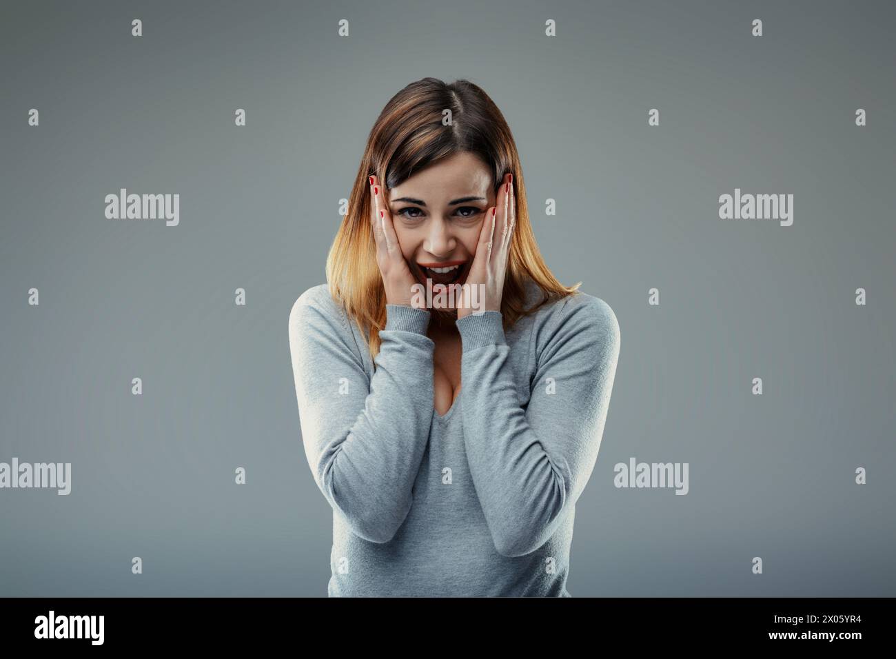 Woman's hands frame a shocked expression, her mouth agape as if ...