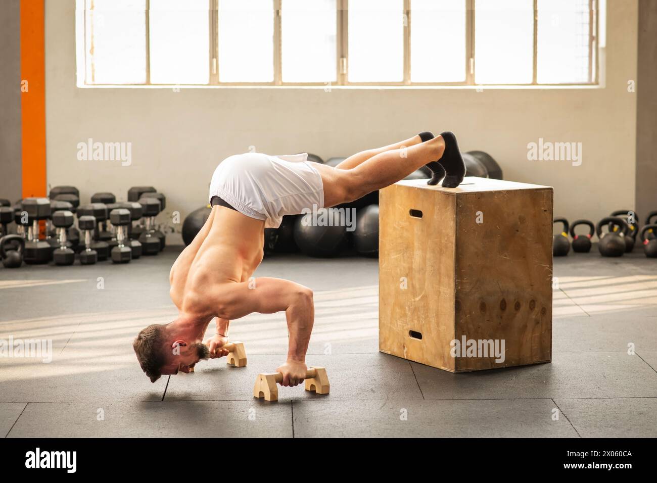 Side view of strong muscular male performing calisthenics box pike push ...