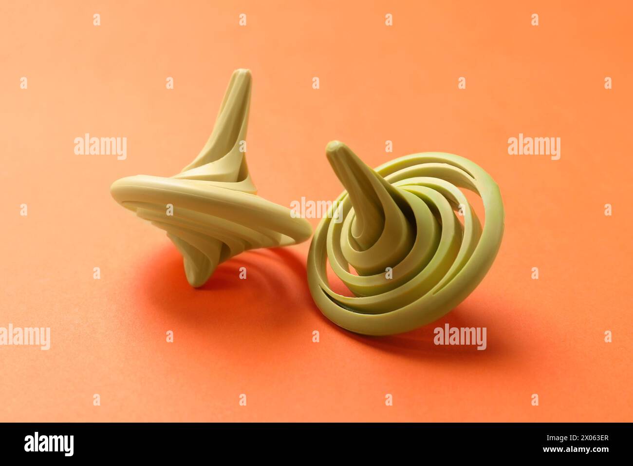 Yellow and green spinning tops on orange background Stock Photo - Alamy