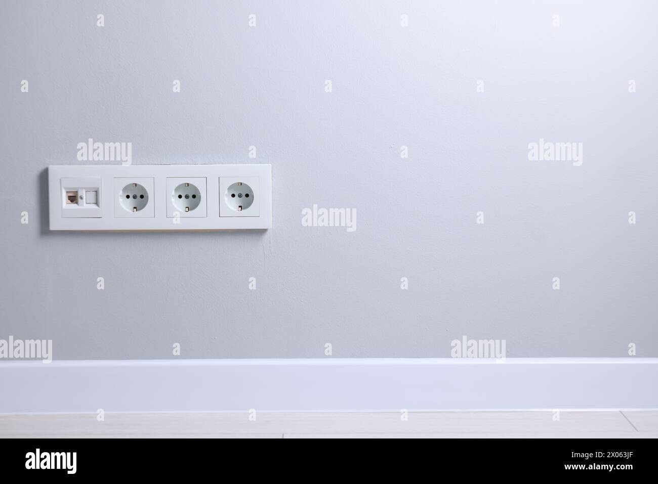 Electric power sockets on light grey wall indoors, space for text Stock ...