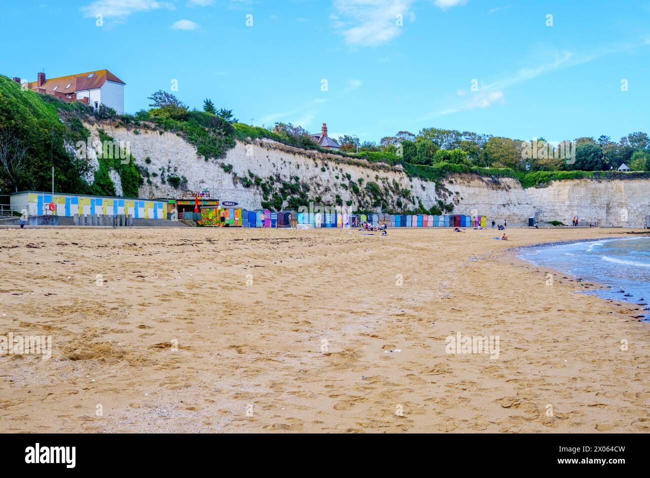 Picturesque sandy beach with row of vibrant, colourful beach huts at ...