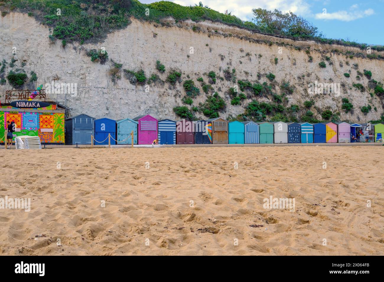 Picturesque sandy beach with row of vibrant, colourful beach huts at ...