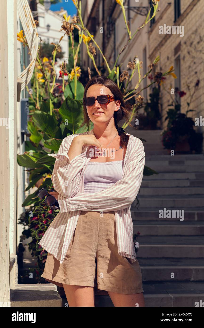 A young girl in sunglasses travels through Europe and poses against the ...