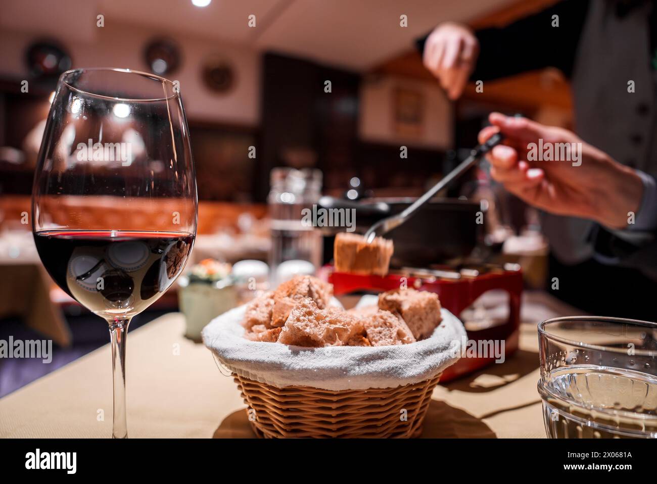 Intimate dining scene with red wine glass and fondue pot in cozy ...