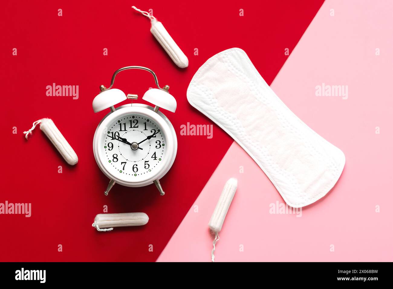 Top view of sanitary pad, menstrual tampons and white alarm clock over ...
