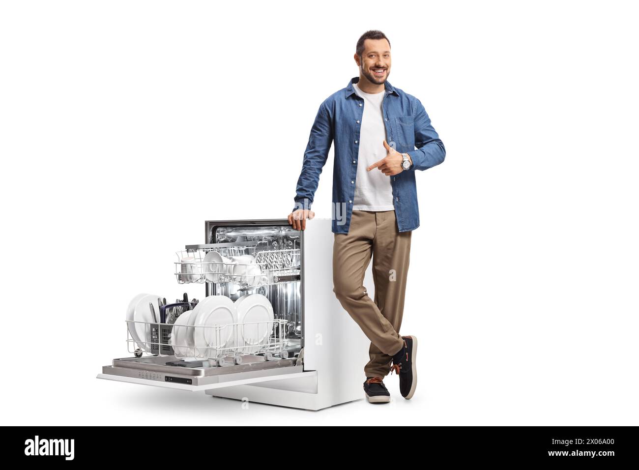 Young man pointing at clean plates in a dishwasher isolated on white ...