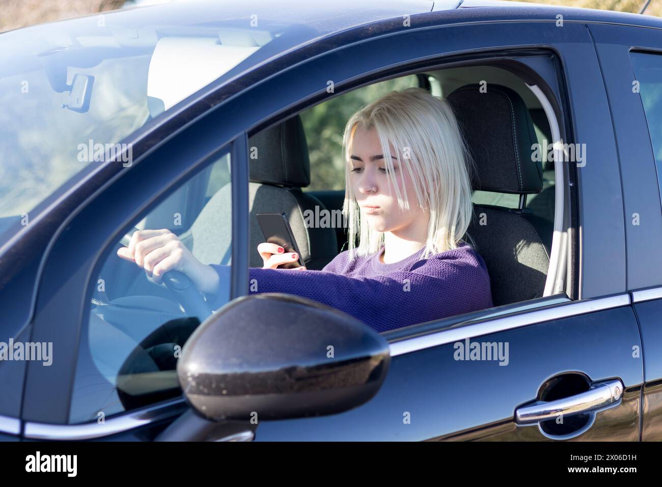 A smiling blonde woman in a purple sweater chatting on her phone while ...