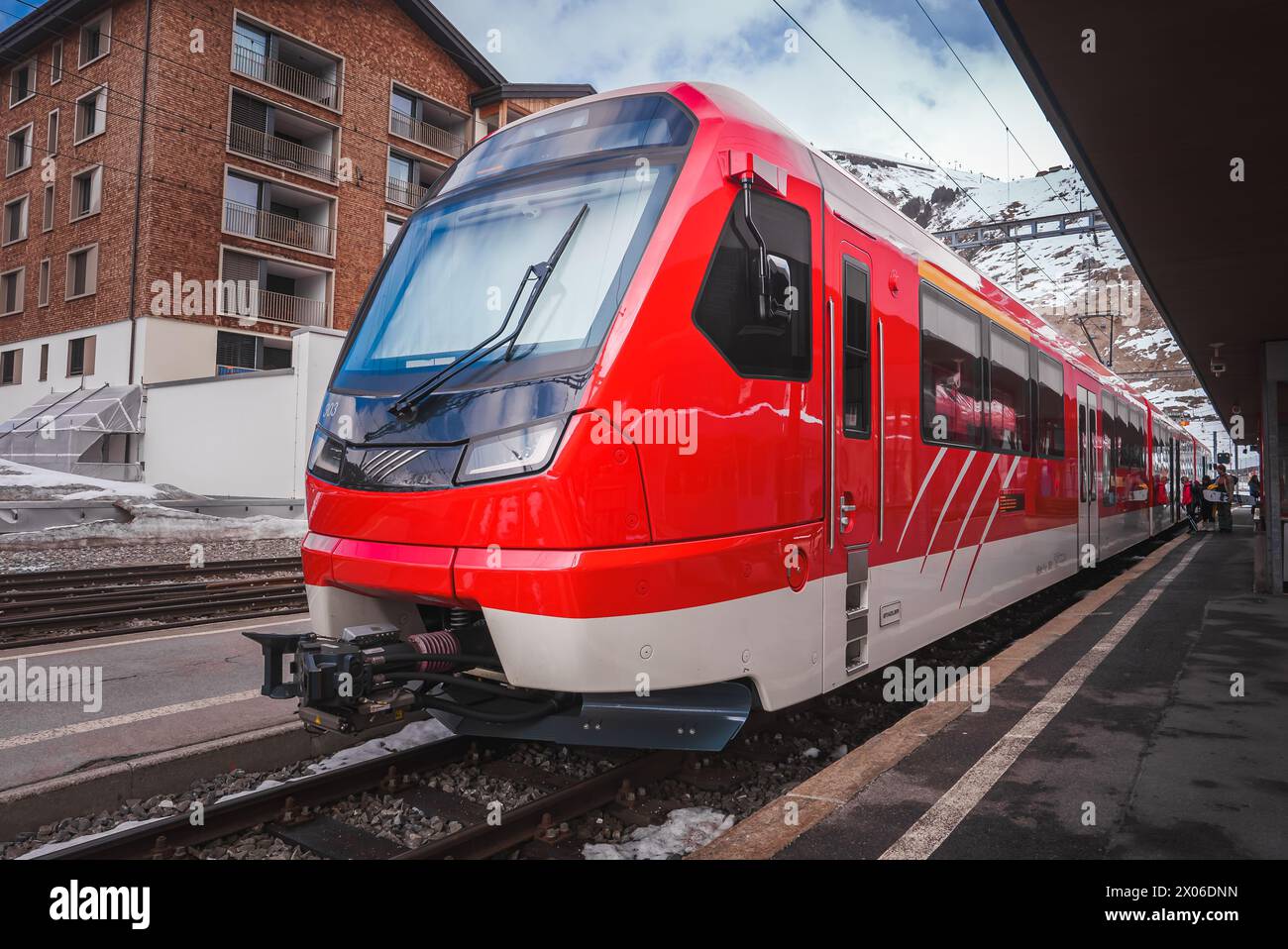 Modern red train at Swiss platform with snow capped mountains Stock ...