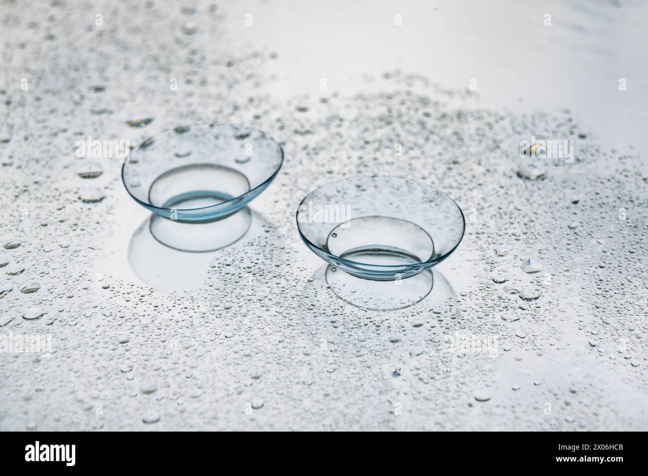 Contact lenses, on mirror surface, with water drops Stock Photo - Alamy
