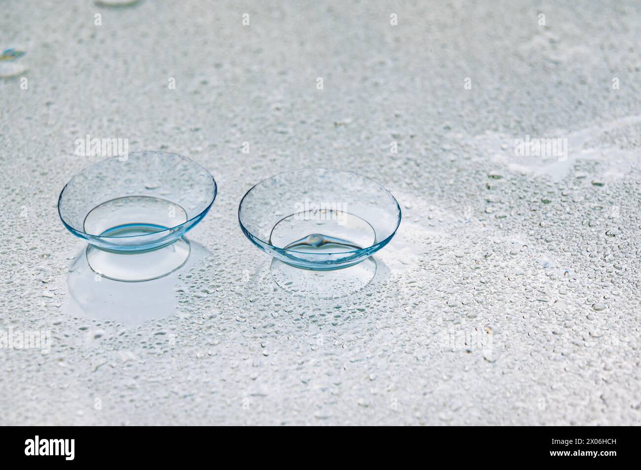Contact lenses, on mirror surface, with water drops Stock Photo - Alamy