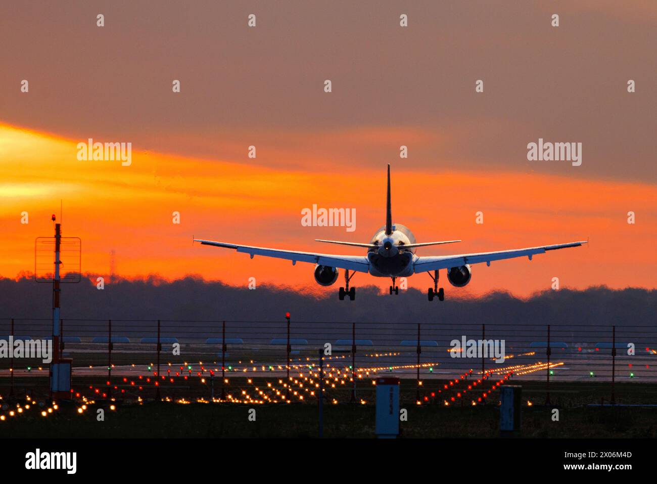 airplane approaching over illuminated runway in the sunset, Germany ...