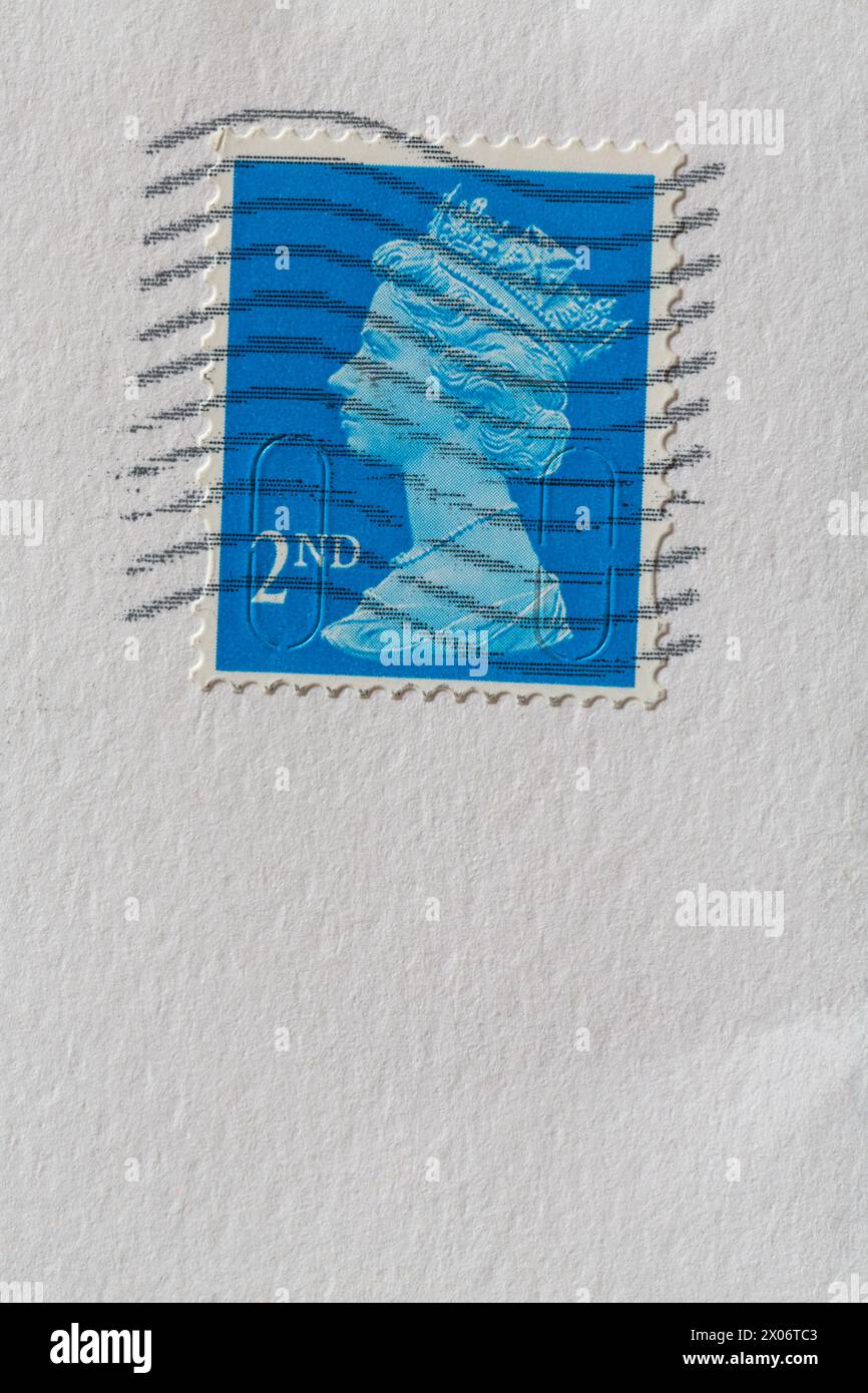 2nd class postage stamp with Queens head stuck on white envelope ...