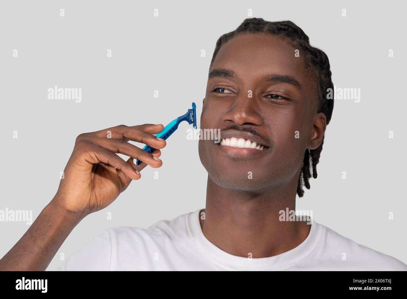 Man shaving with a blue razor on white background Stock Photo - Alamy