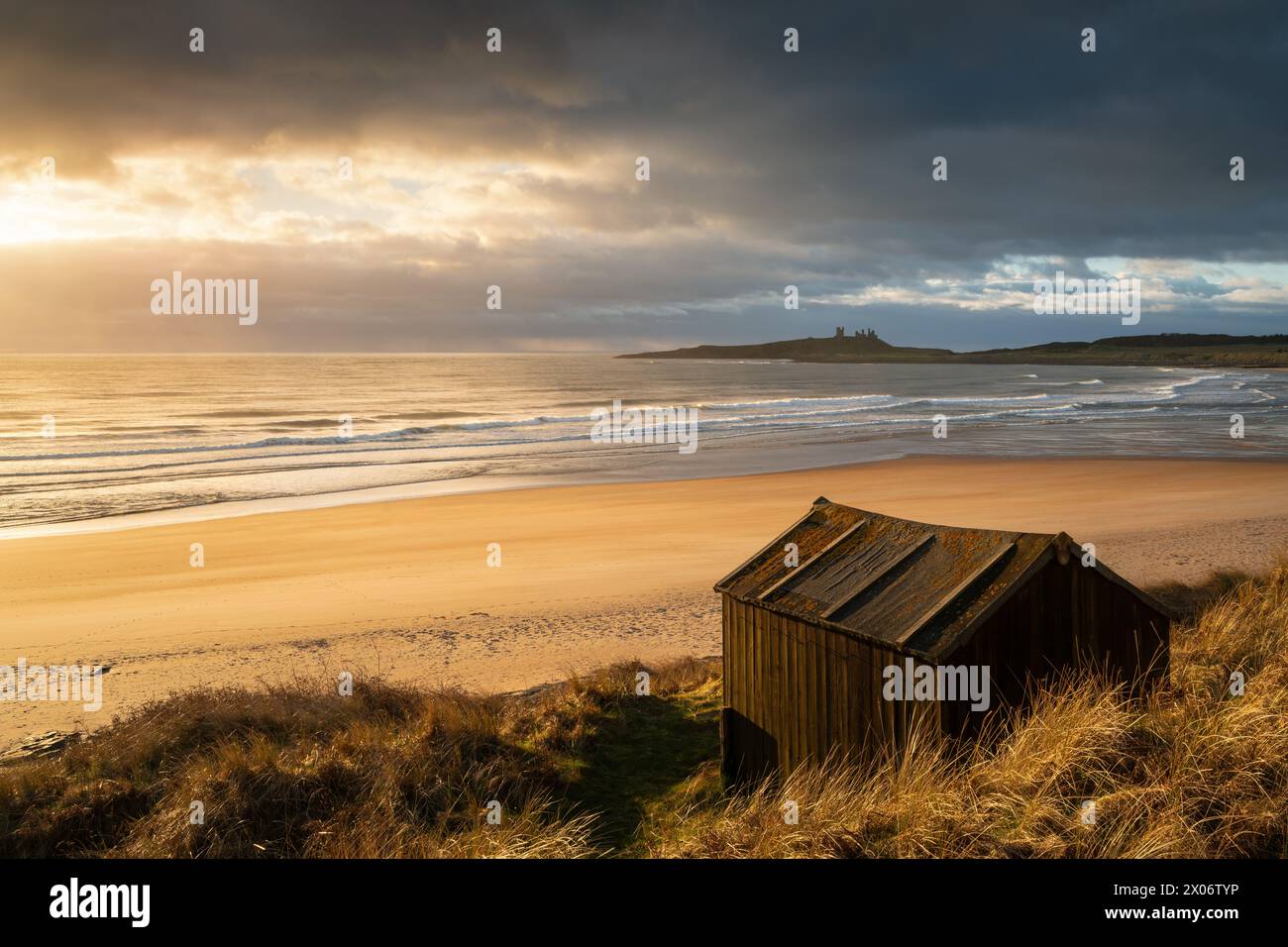 Fierce golden light highlights a beach hut over Embleton Bay at sunrise ...