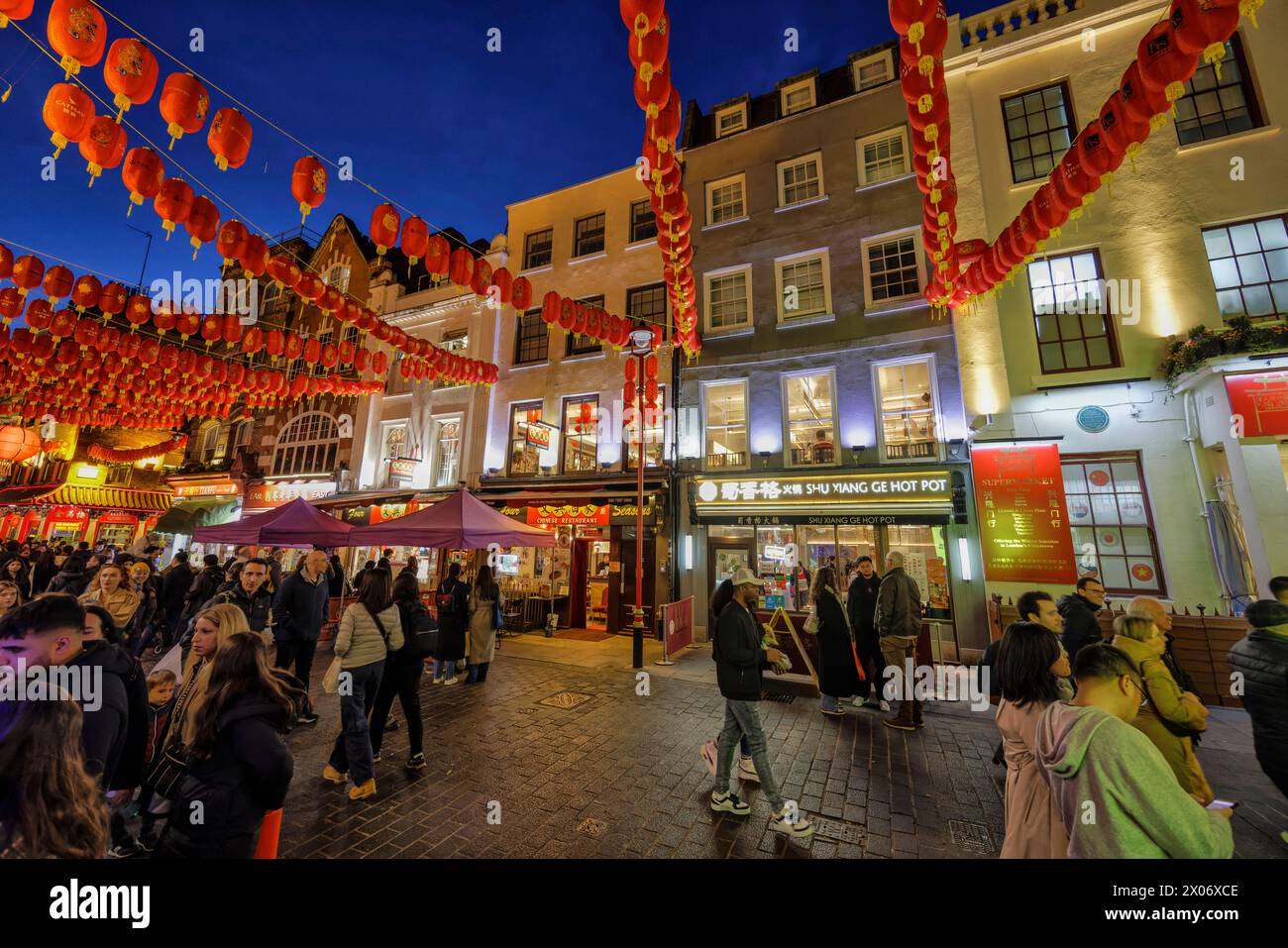 People and colourful Chinese lanterns by restaurants in busy Gerrard Street centre of Chinatown ...